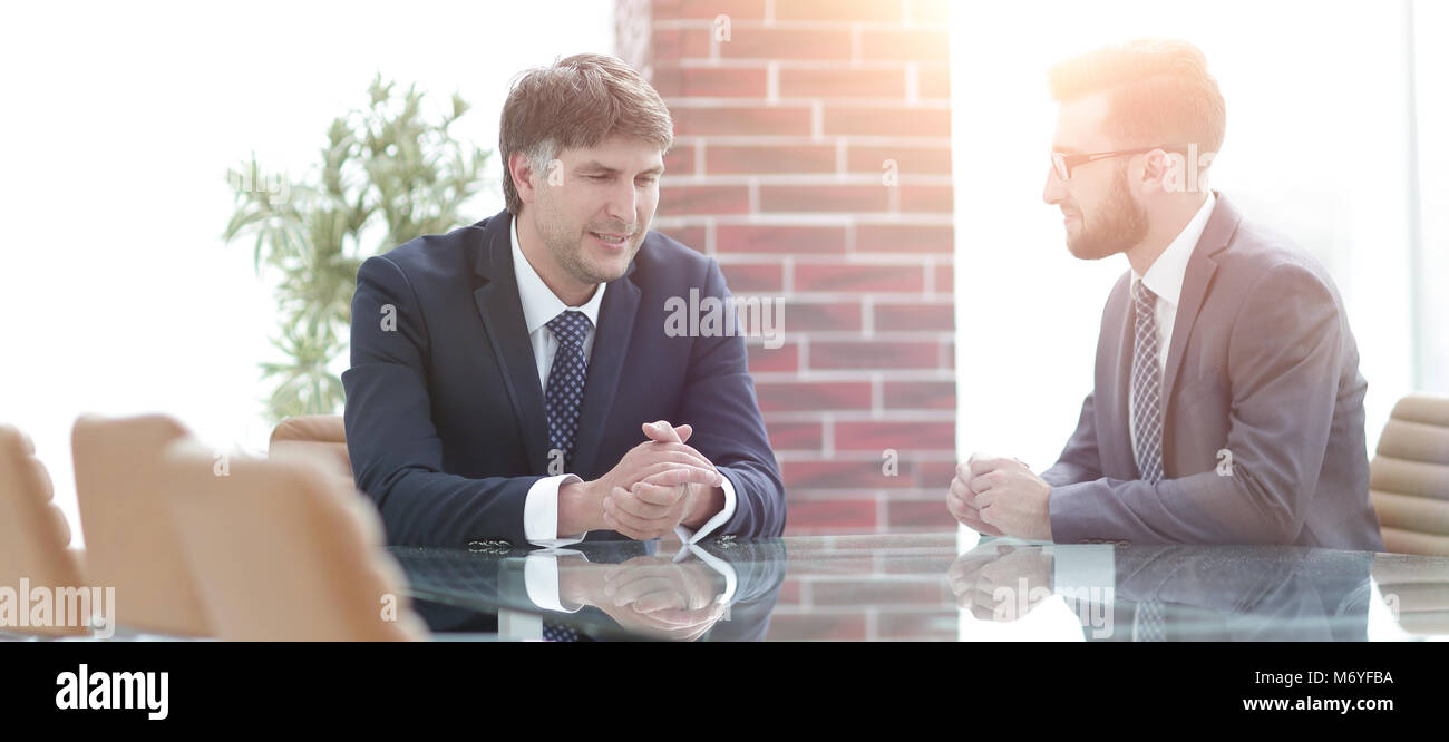 Two businessmen discussing tasks sitting at office table Stock Photo ...