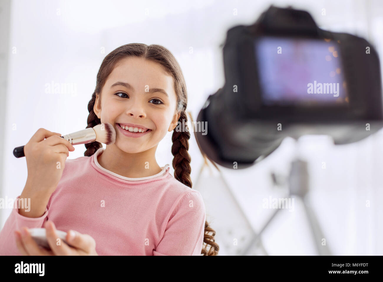Adorable girl smiling while filming makeup tutorial Stock Photo - Alamy