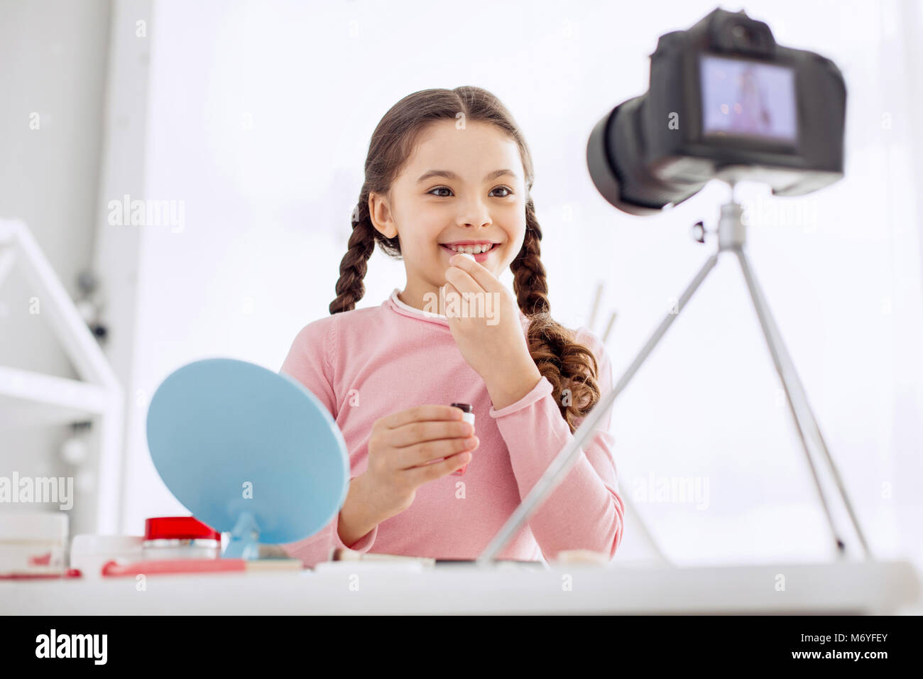 Charming girl applying lip balm while filming tutorial Stock Photo - Alamy