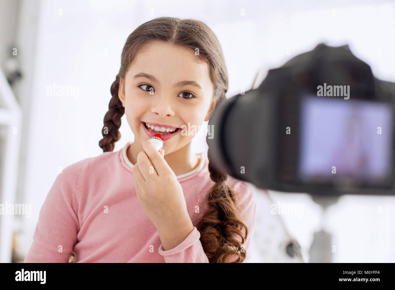 Pretty girl putting on lip balm during makeup tutorial Stock Photo - Alamy