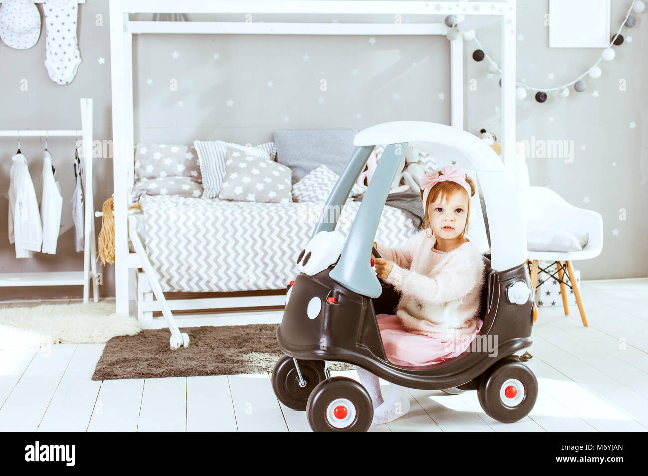 Little beautiful girl sitting in a toy car Stock Photo - Alamy