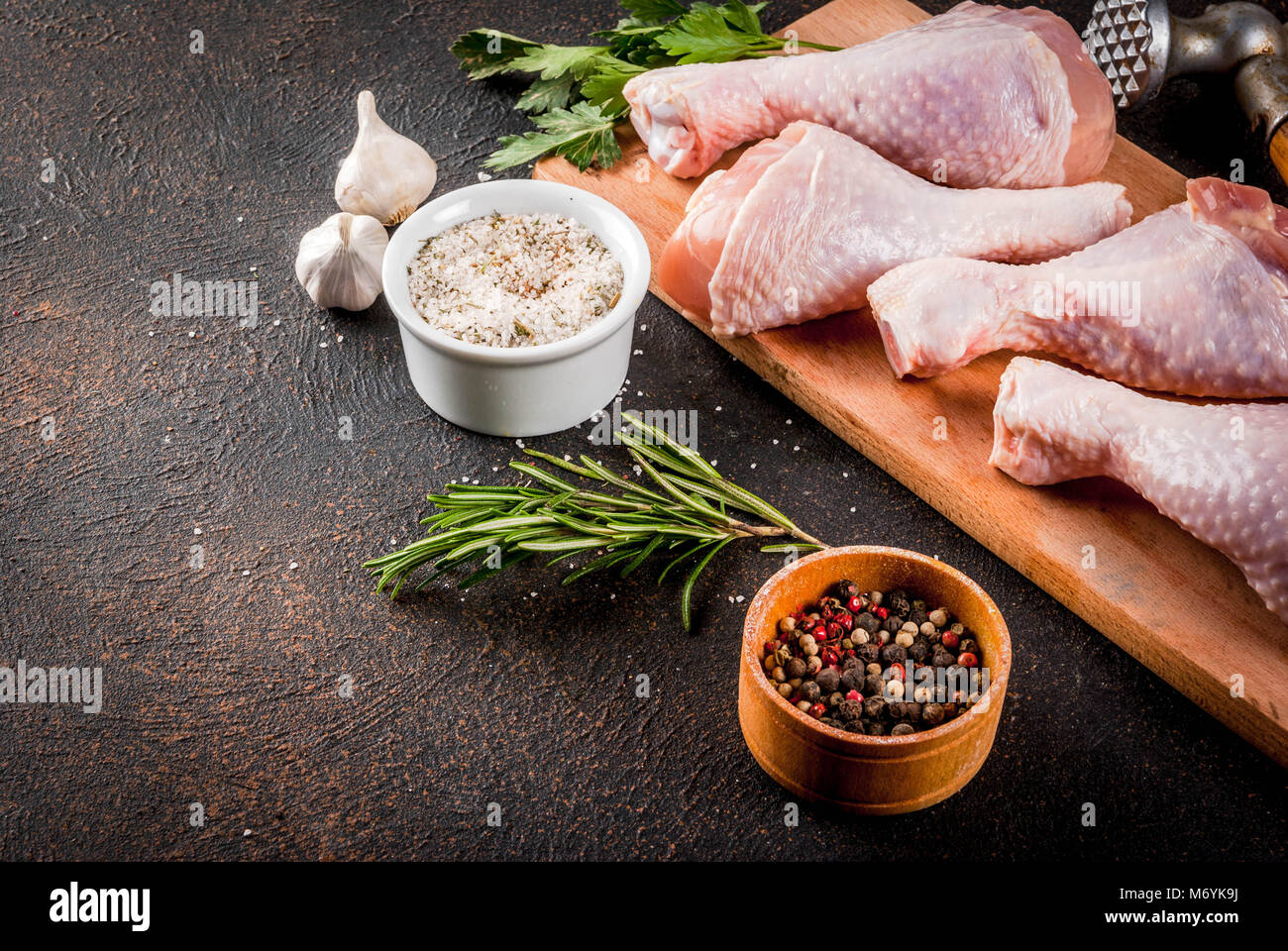 Raw meat, chicken legs, with herbs and spices n dark rusty background ...