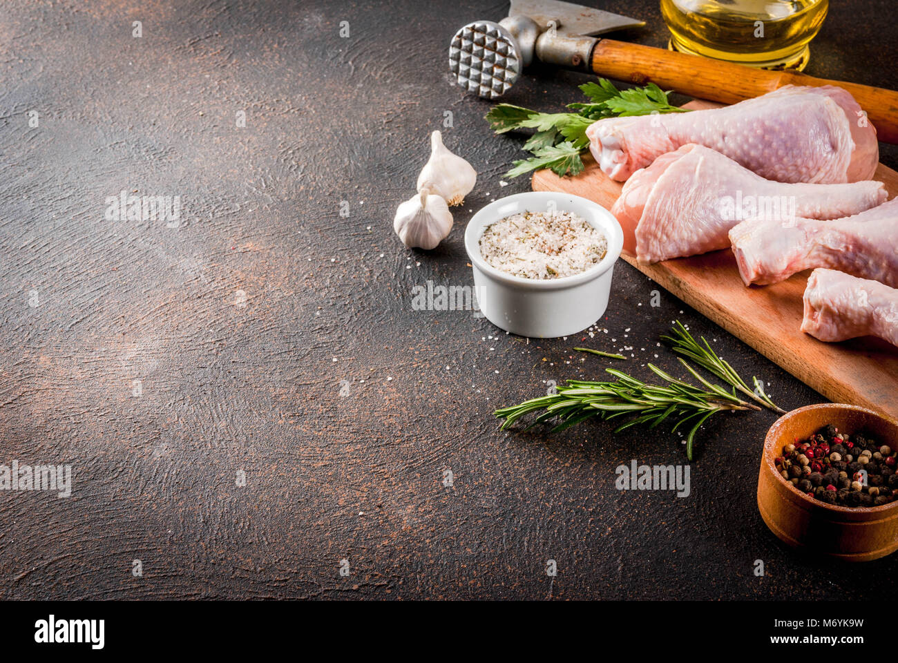 Raw meat, chicken legs, with herbs and spices n dark rusty background ...