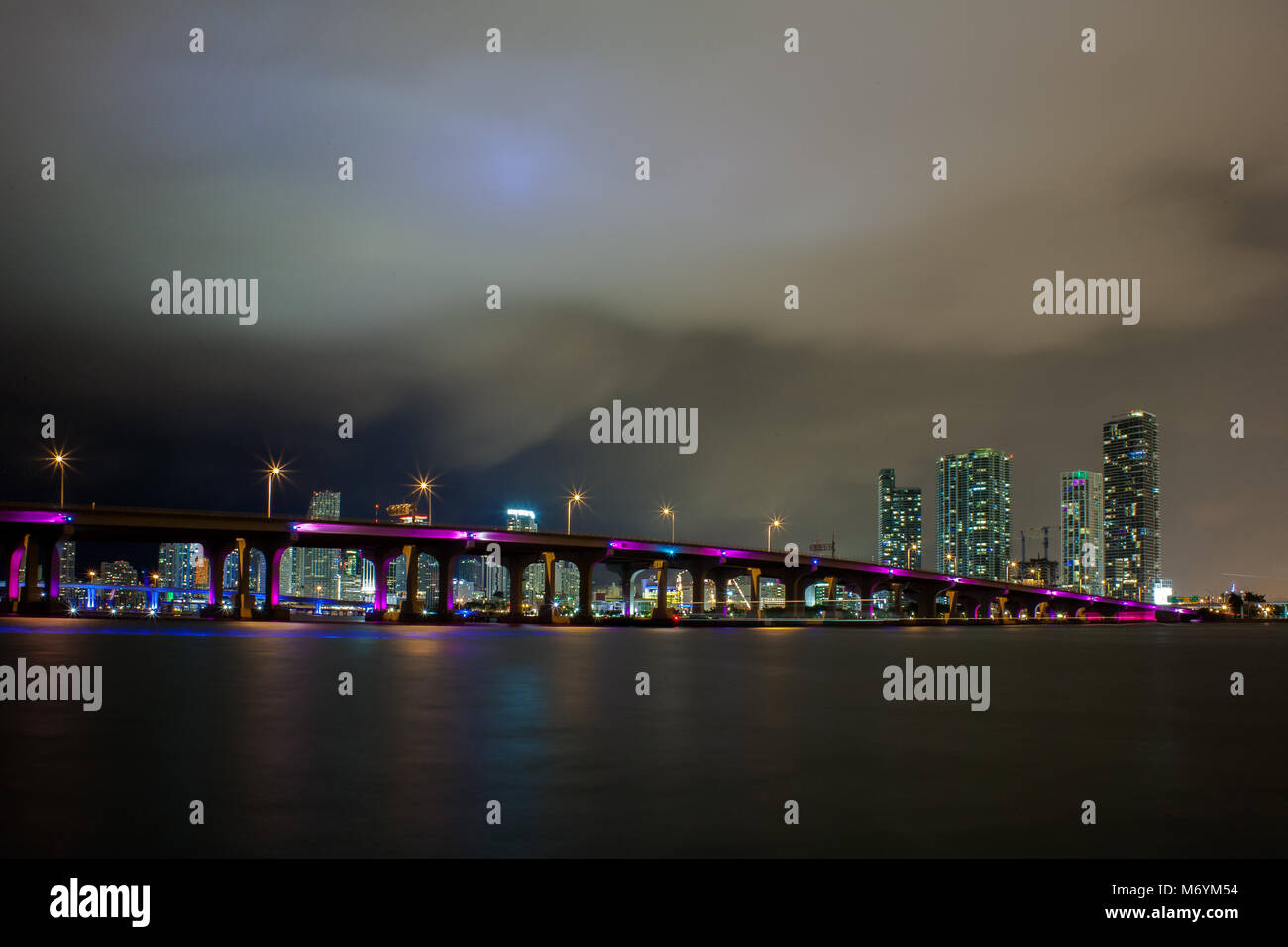 View of MacArthur Causeway bridge in Miami at night over water. Moon ...