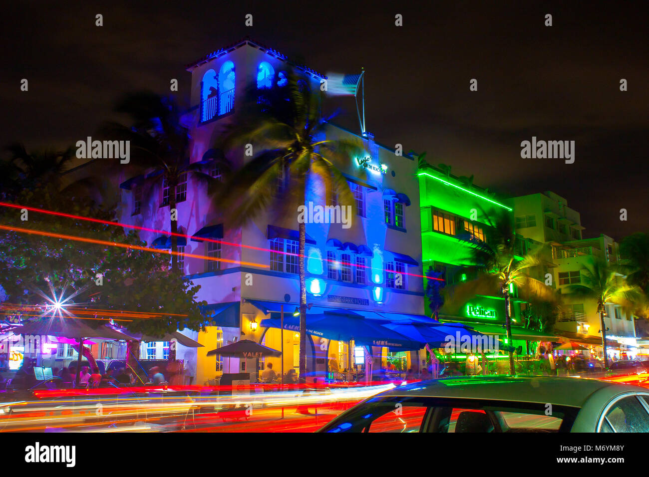 Ocean Drive in Miami at night with vibrant street colours. Cars passing ...