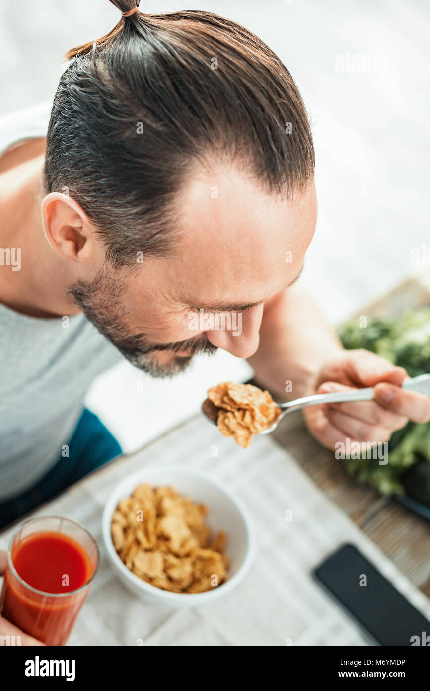 Calm unshaken man sitting and having breakfast Stock Photo - Alamy