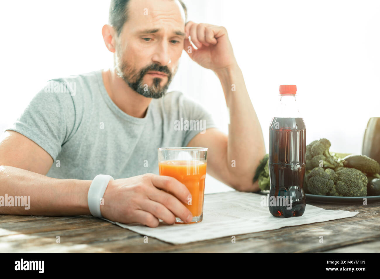 Disturbed upset man sitting and looking at a glass Stock Photo - Alamy