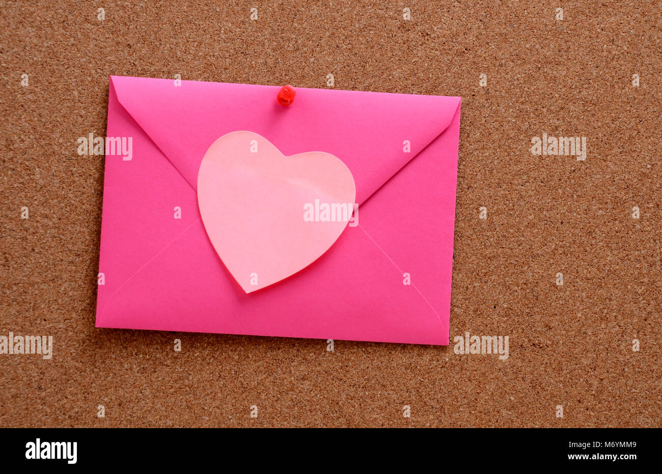 Heart shaped paper notes with envelope pinned into brown corkboard ...
