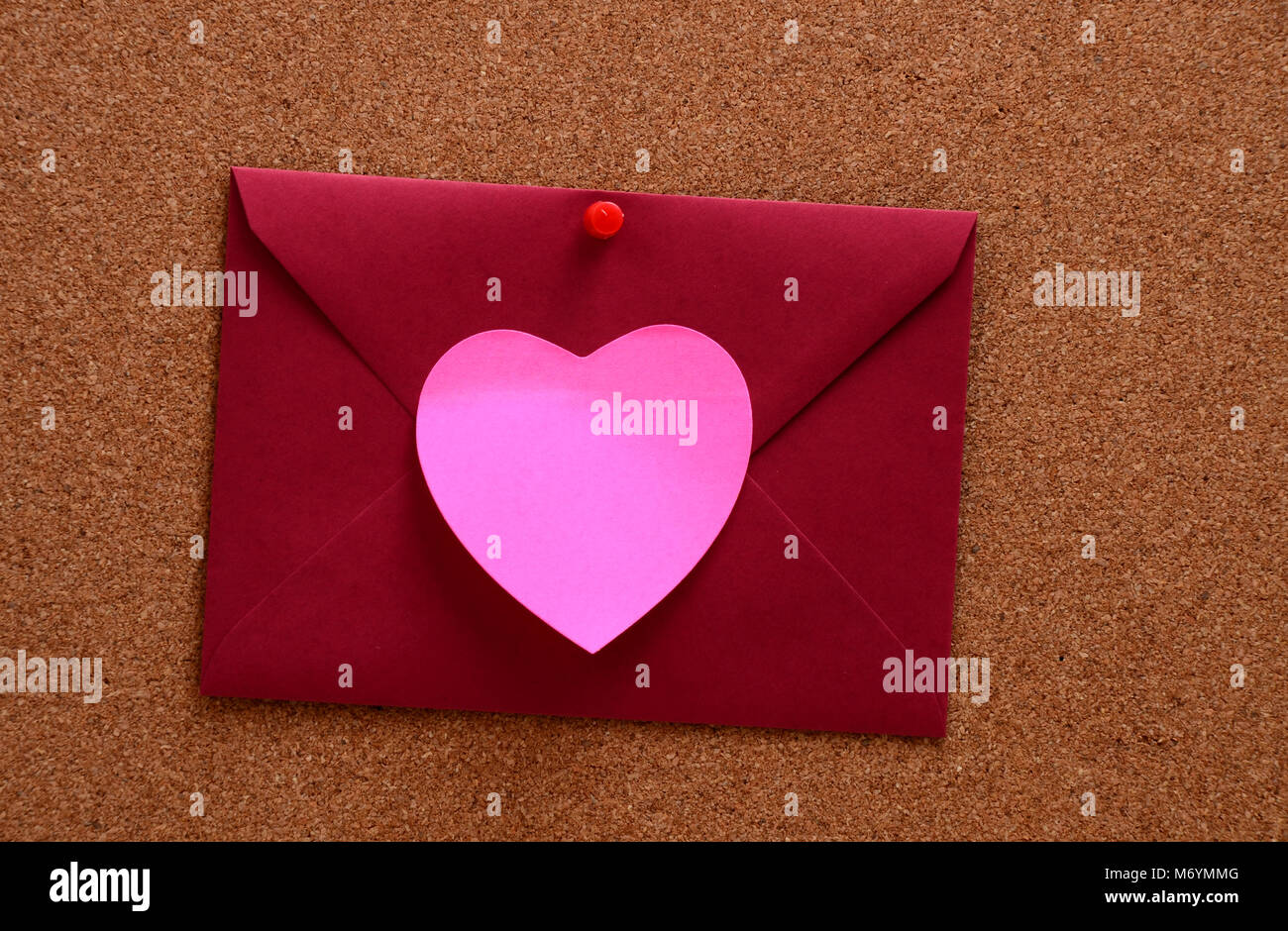 Heart shaped paper notes with envelope pinned into brown corkboard ...