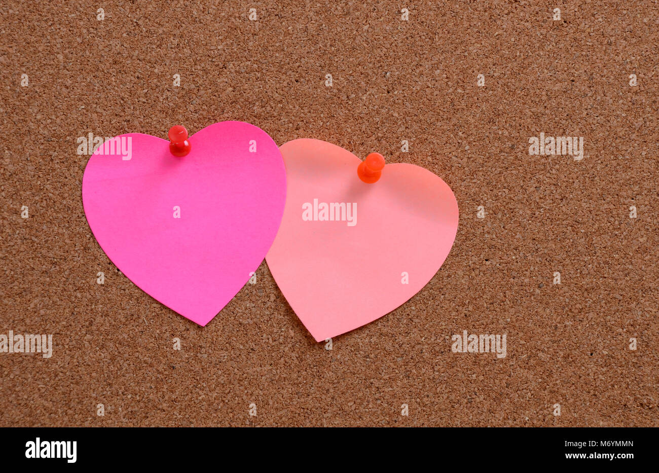 Heart shaped paper notes with envelope pinned into brown corkboard ...