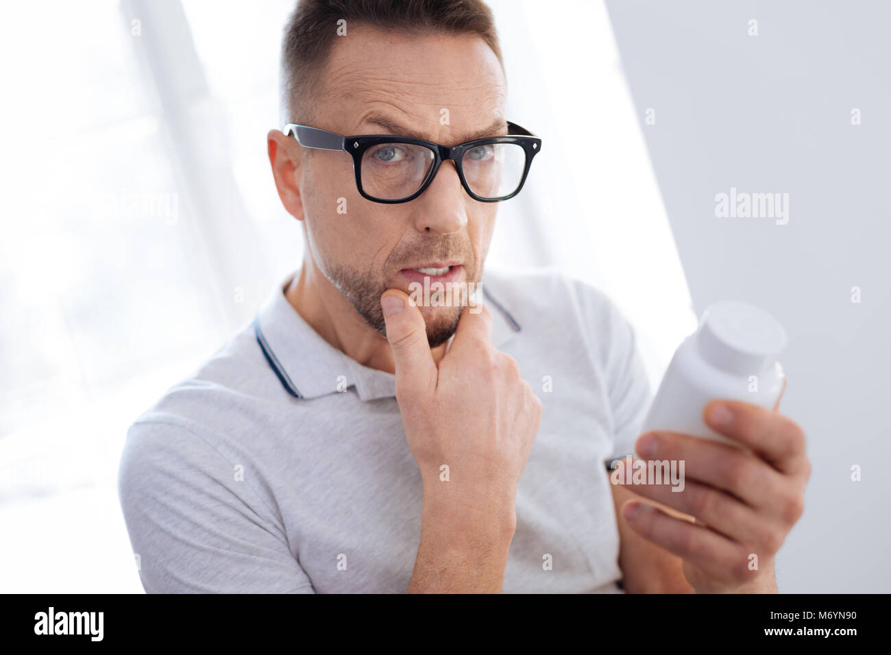 Charming wistful man scrutinizing biohacking drug Stock Photo - Alamy