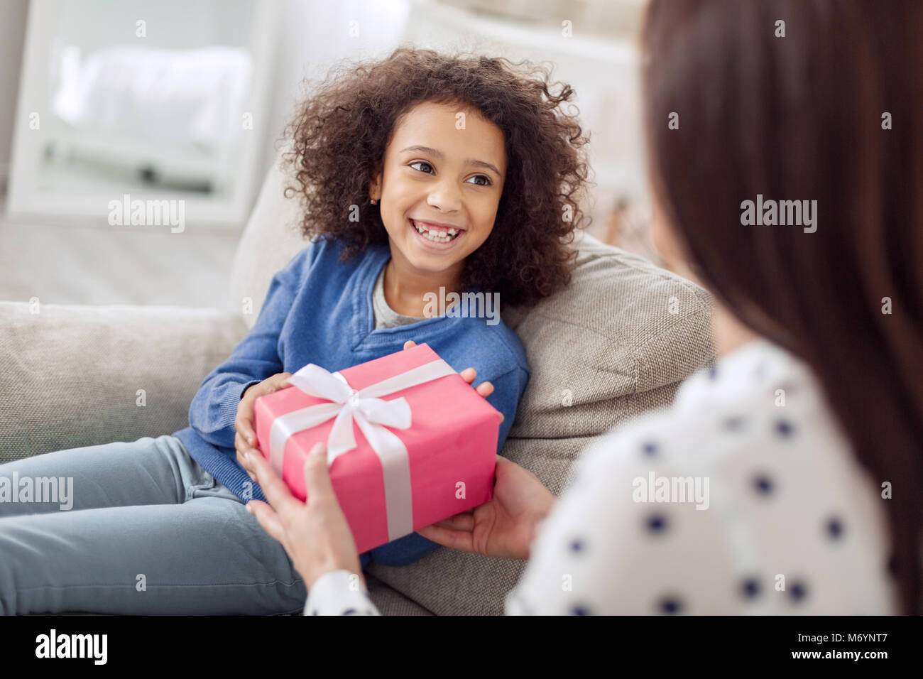 Caring mother giving her daughter a gift Stock Photo - Alamy