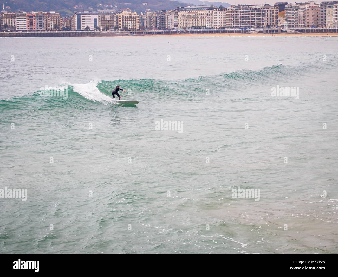 Lonely surfer is surfing on wawes at La Concha Beach in San Sebastian ...
