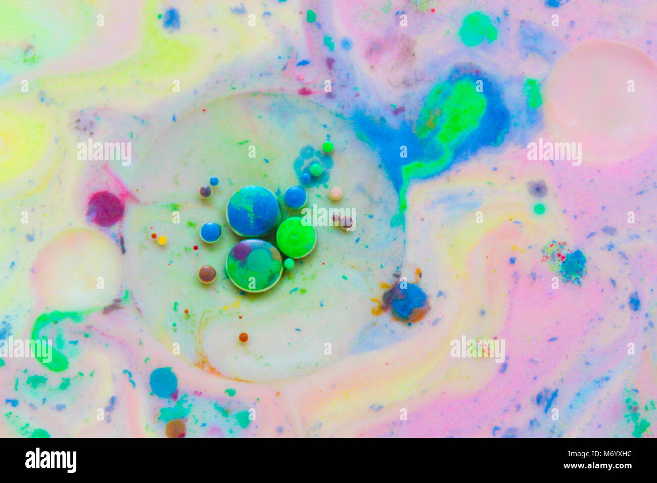 Abstract background, pink and green color mix together in milk. Macro ...