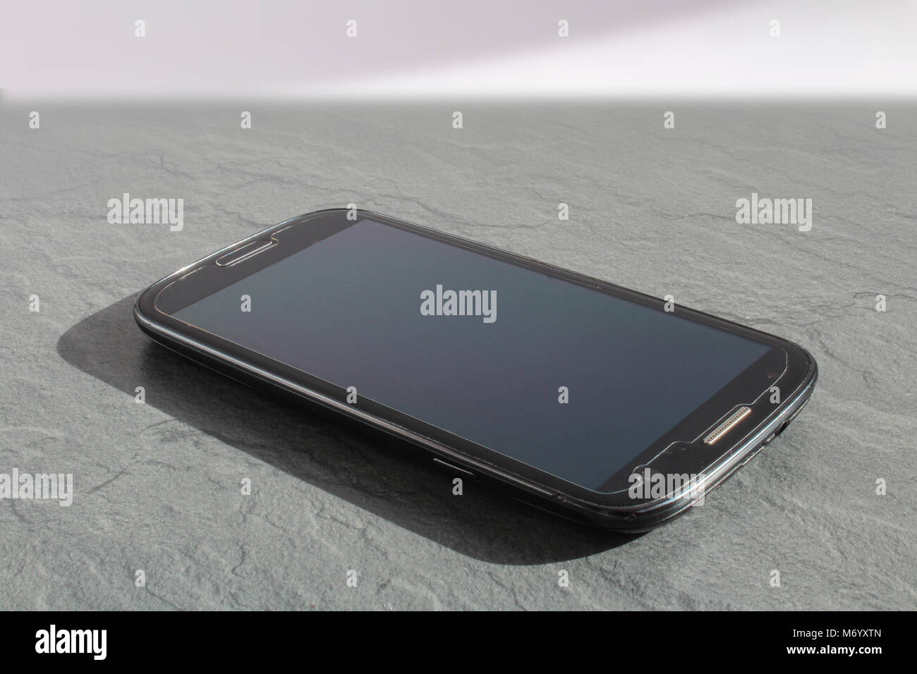 Mobile phone on dark grey stone texture Stock Photo - Alamy