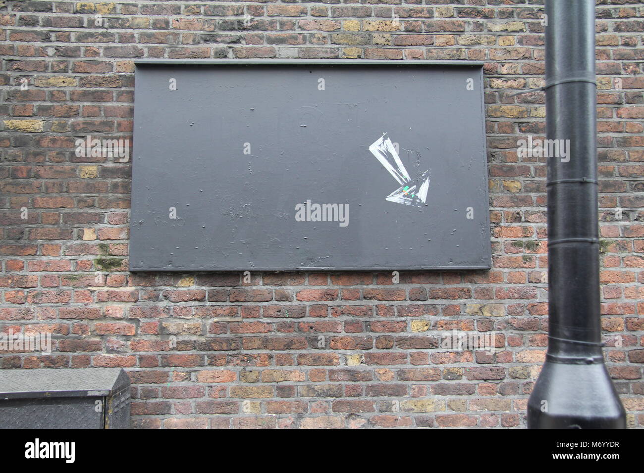 Sign on Brickwork wall in west London, Arrow has been stencilled onto ...
