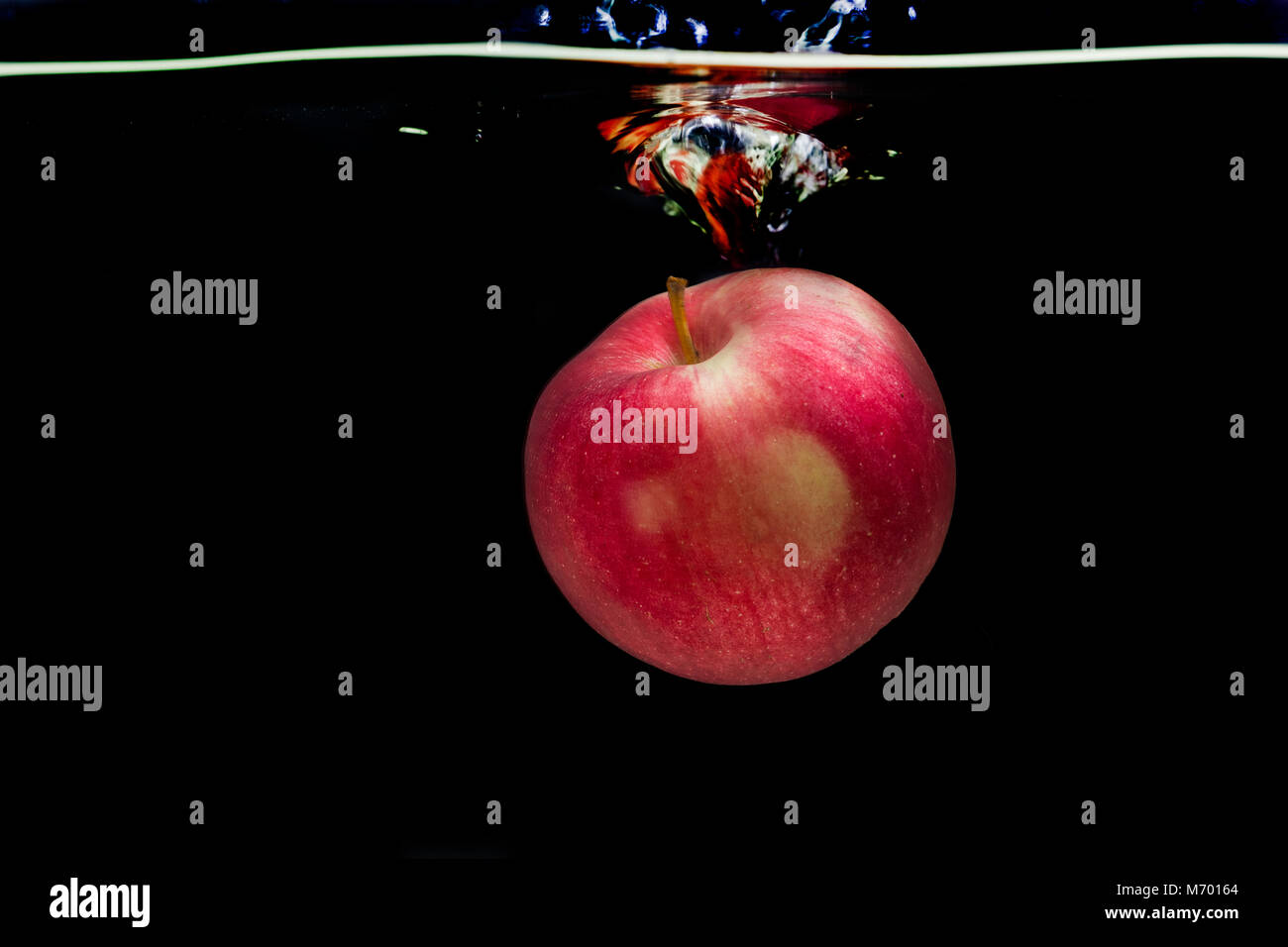 Apple falls into the water and makes a splash Stock Photo - Alamy