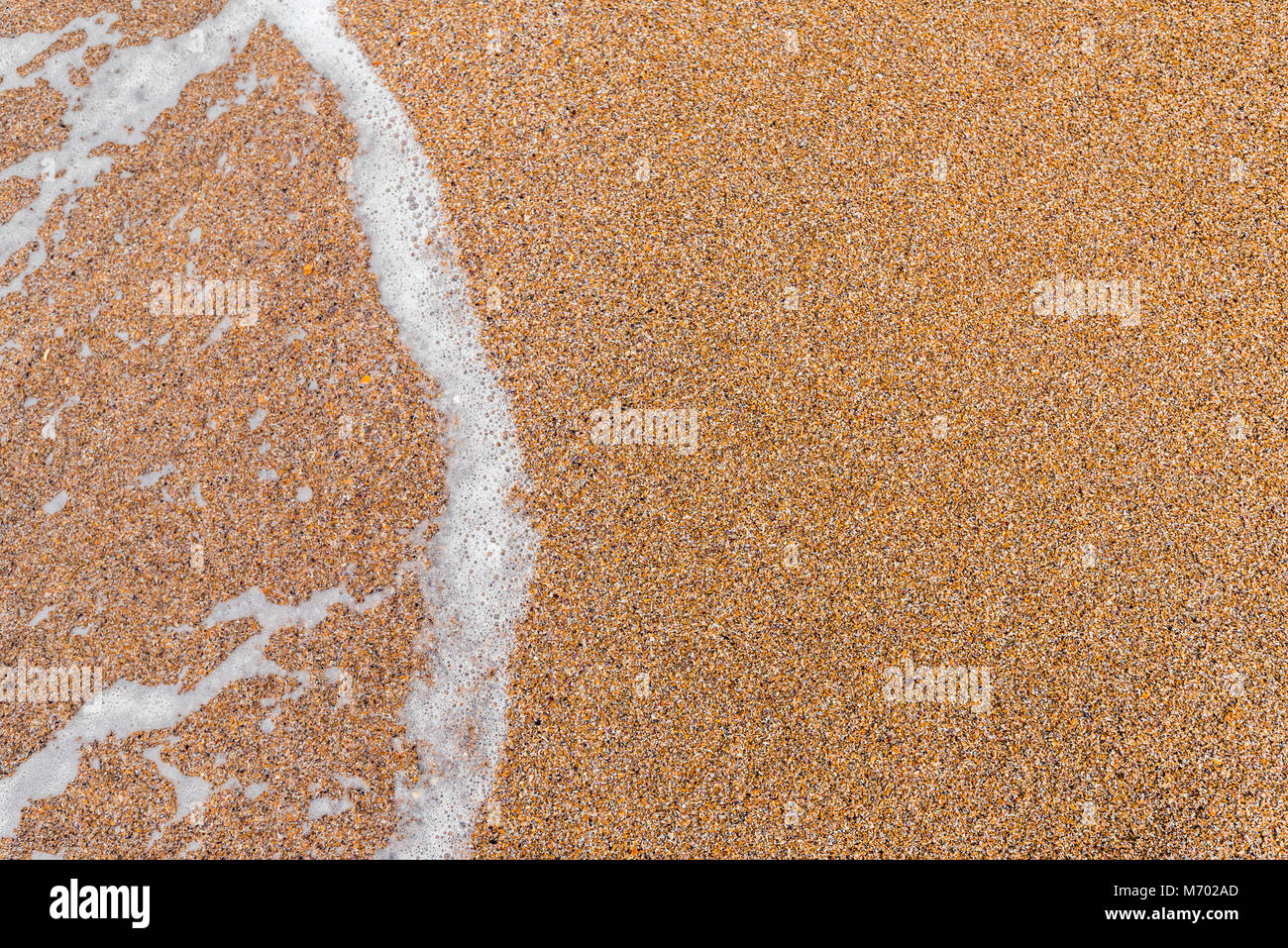 Golden sand and sea wave background Stock Photo - Alamy