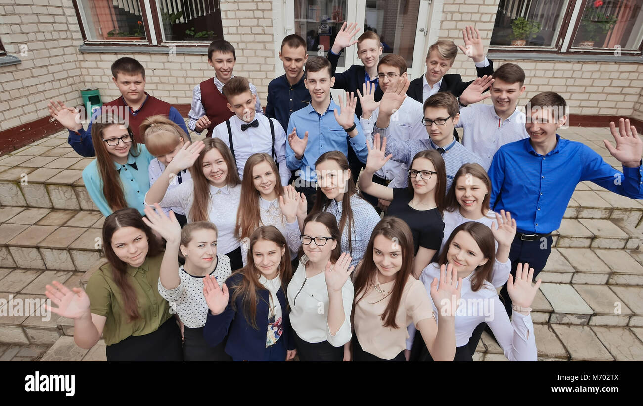 A large company of happy students waving their hands on the steps of ...
