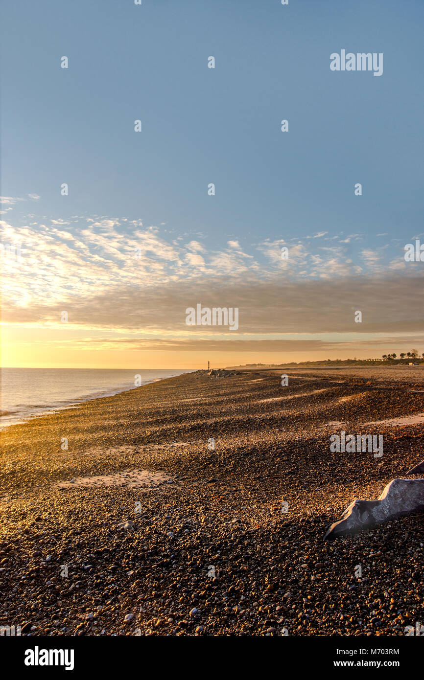 Looking asking the beach down a shingle shore line at sunrise Stock ...