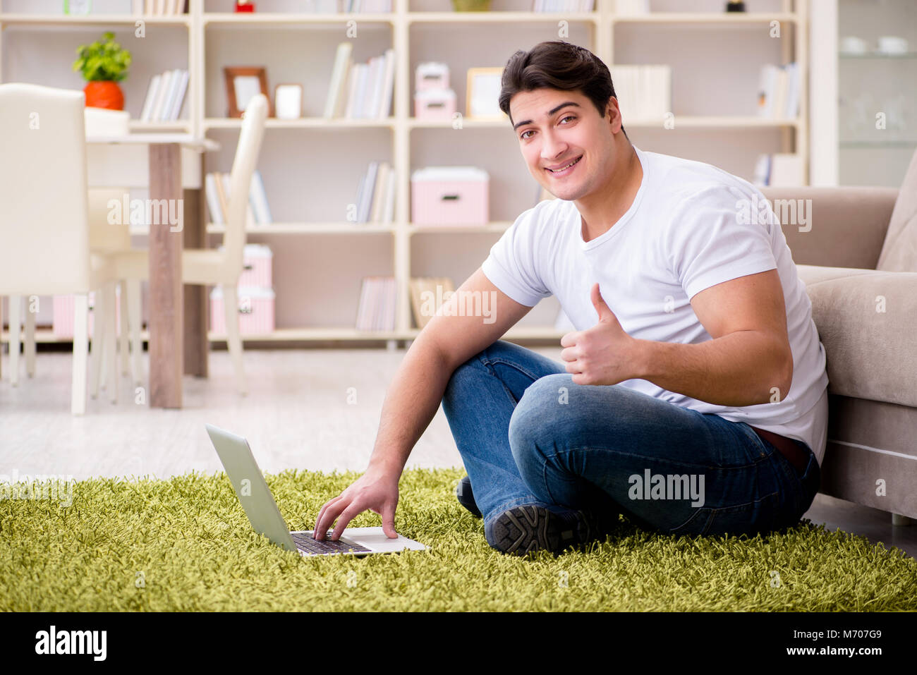 Man working on laptop at home on carpet floor Stock Photo - Alamy