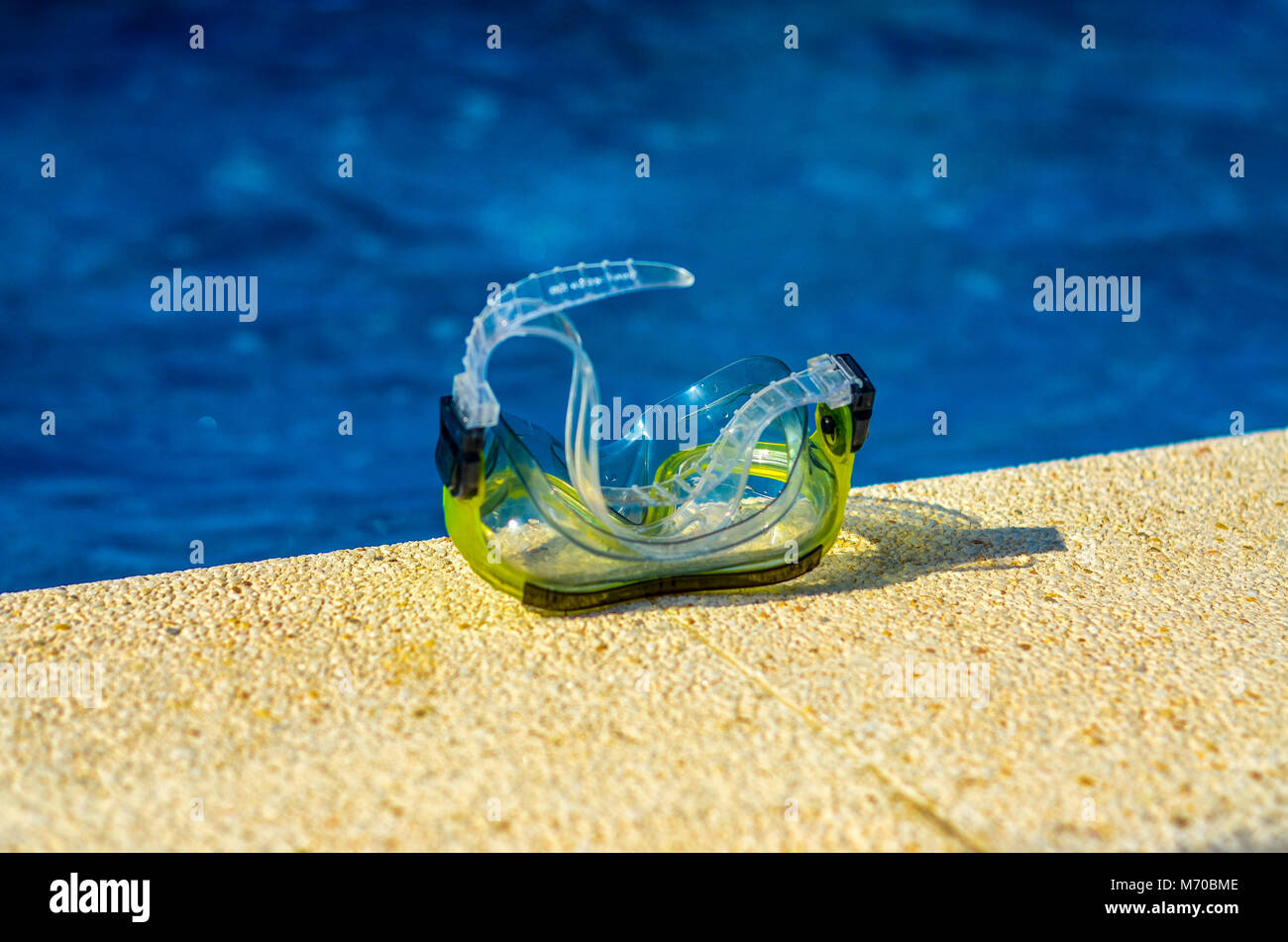 Yellow diving mask by the side of a clear blue pool Stock Photo - Alamy