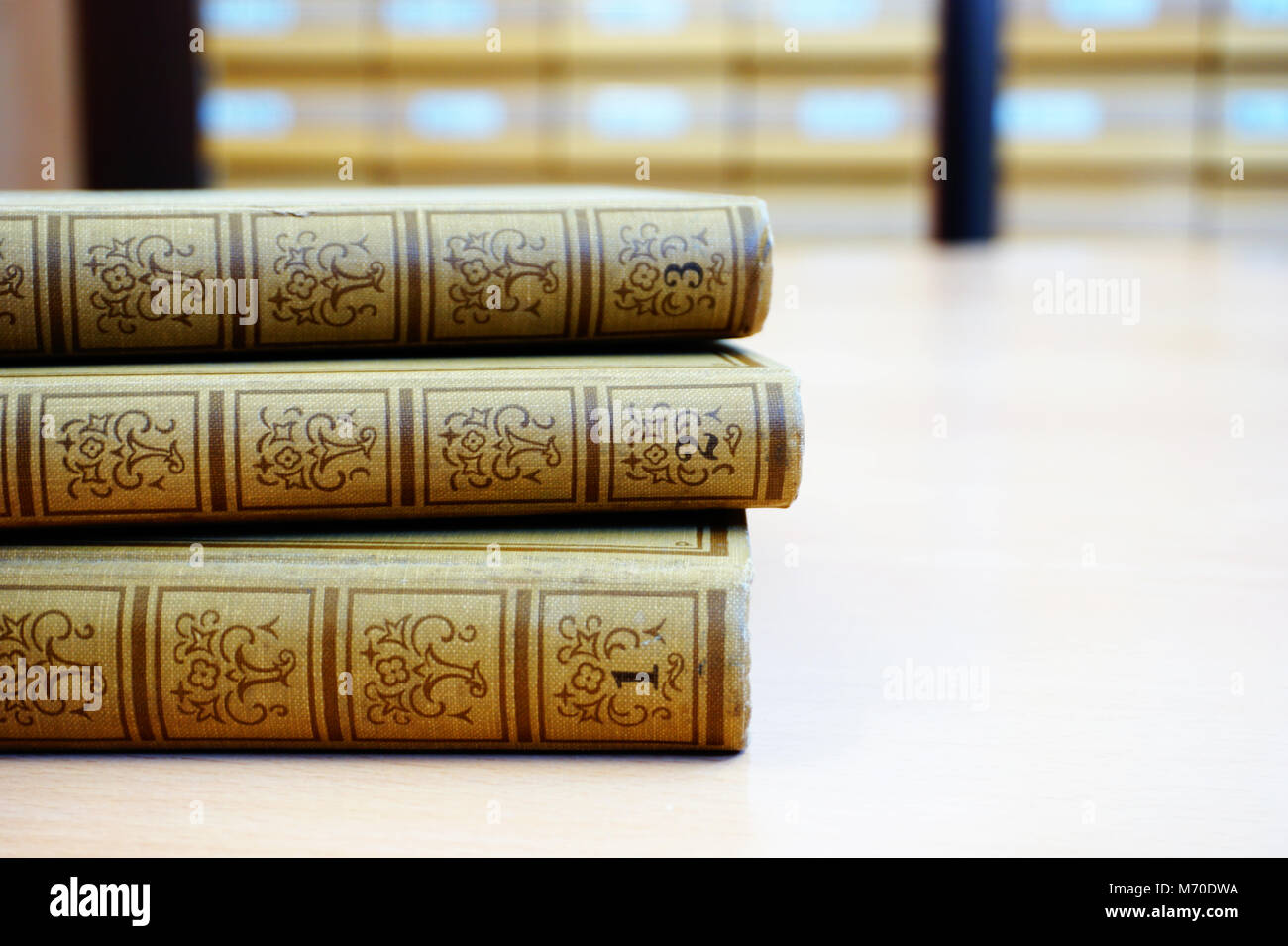 Old encyclopedia in three parts on the desk in the library with blurry ...