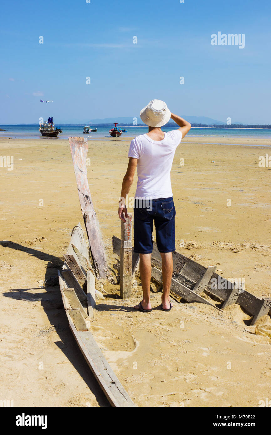 Young stranger standing on the shattered boat and looks into the ...