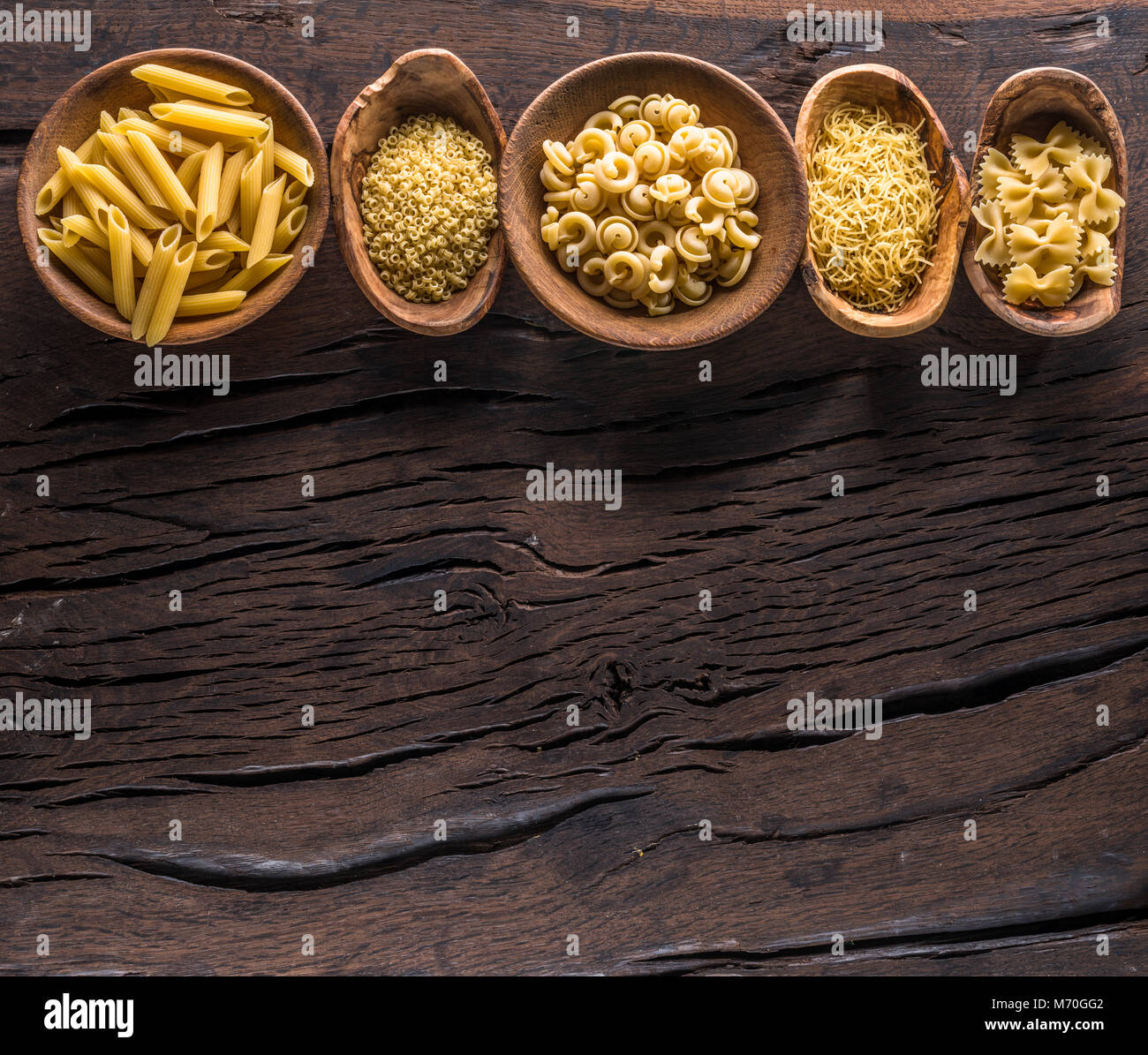 Different pasta types in wooden bowls on the table. Top view Stock ...