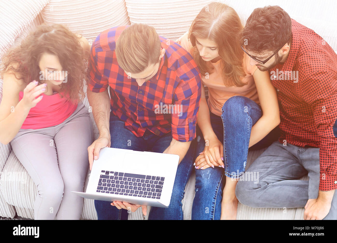 group of friends with laptop sitting on the couch Stock Photo - Alamy