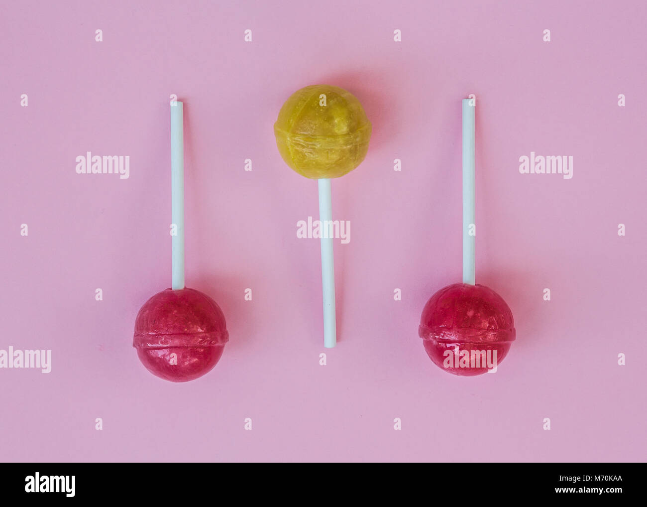 Minimalistic composition of two red lollipops and one yellow one. March ...