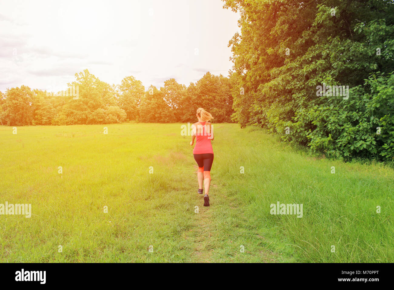 Young woman running from back with strong light Stock Photo - Alamy