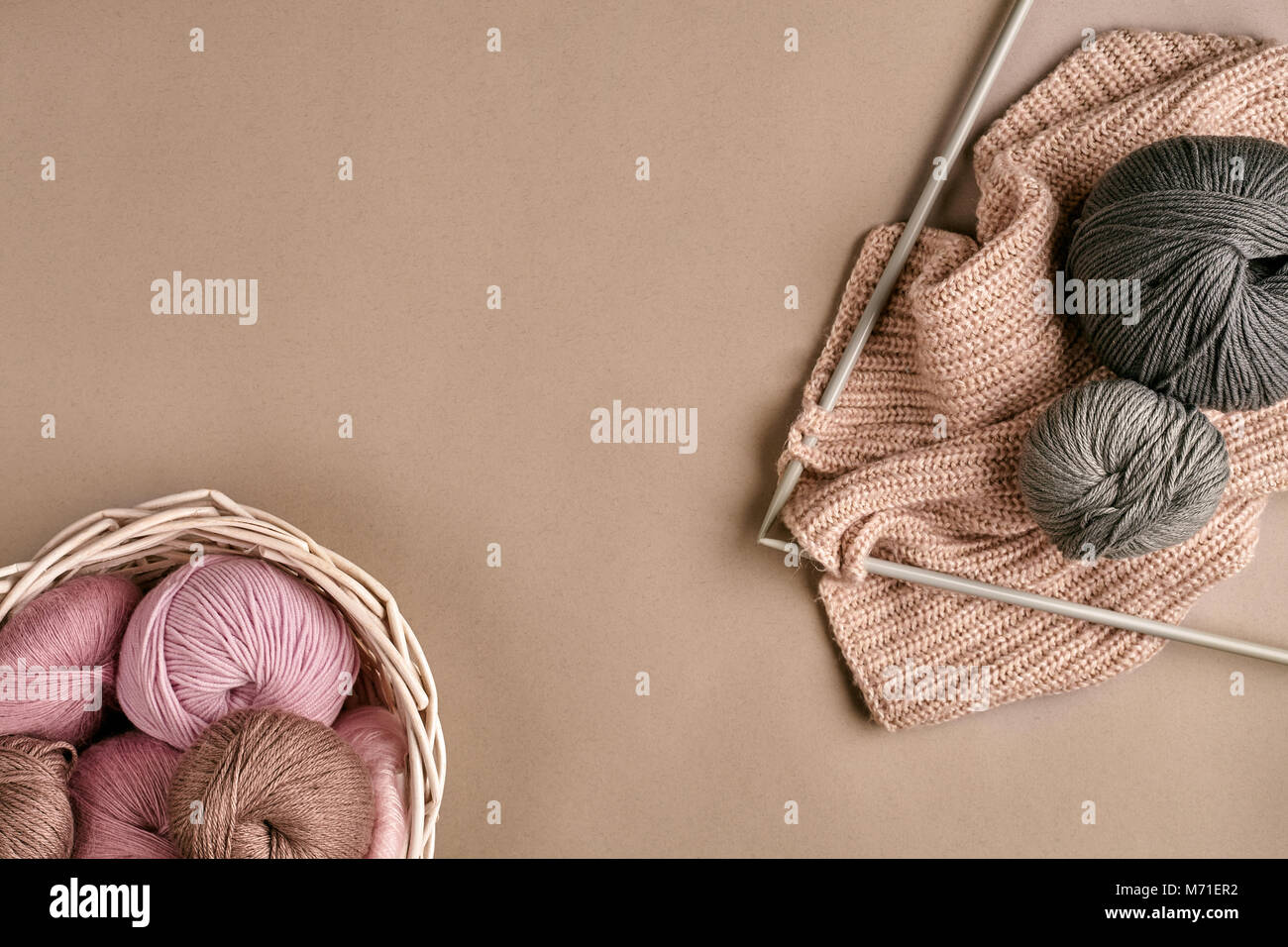 Balls of merino wool yarn, knitting on knitting needles on a beige ...
