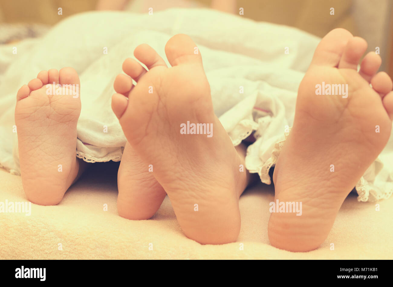 Baby feet from under the blanket on the bed Stock Photo - Alamy