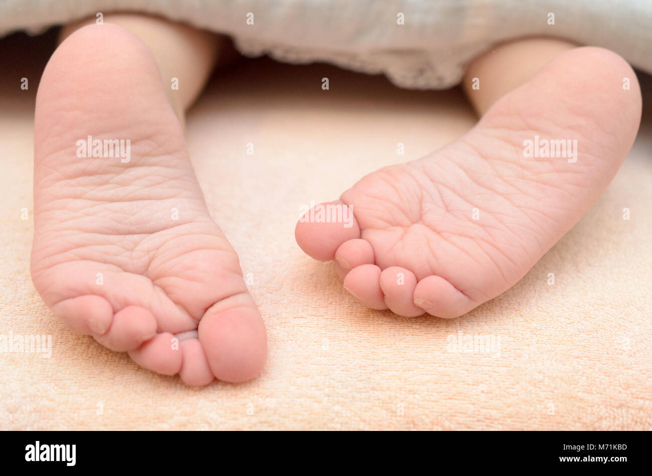 Baby feet from under the blanket on the bed Stock Photo - Alamy