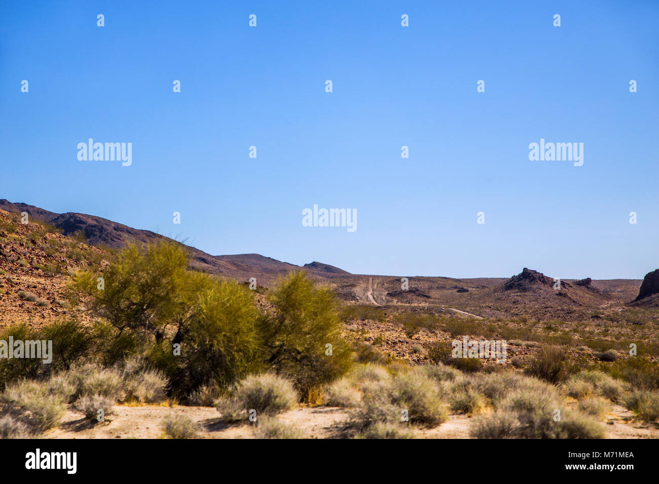 A marrow trail in the distance cutting through the Mojave desert in a ...