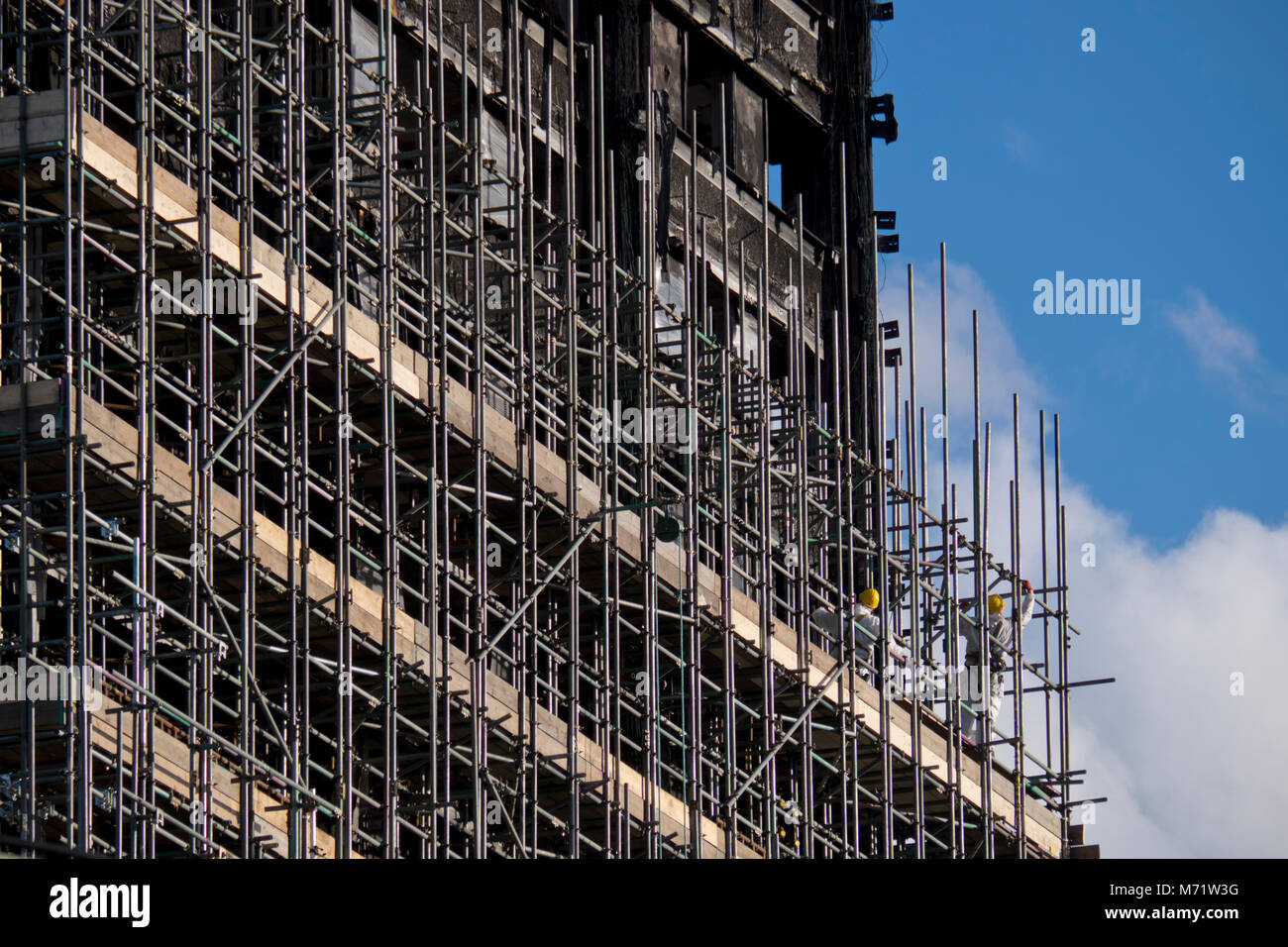 Construction workers building scaffolding before demolition of burnt ...