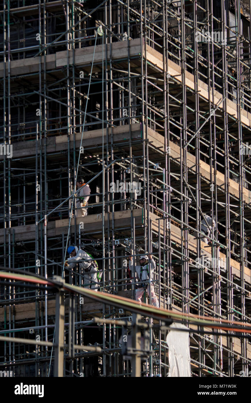 Construction workers building scaffolding before demolition of burnt ...