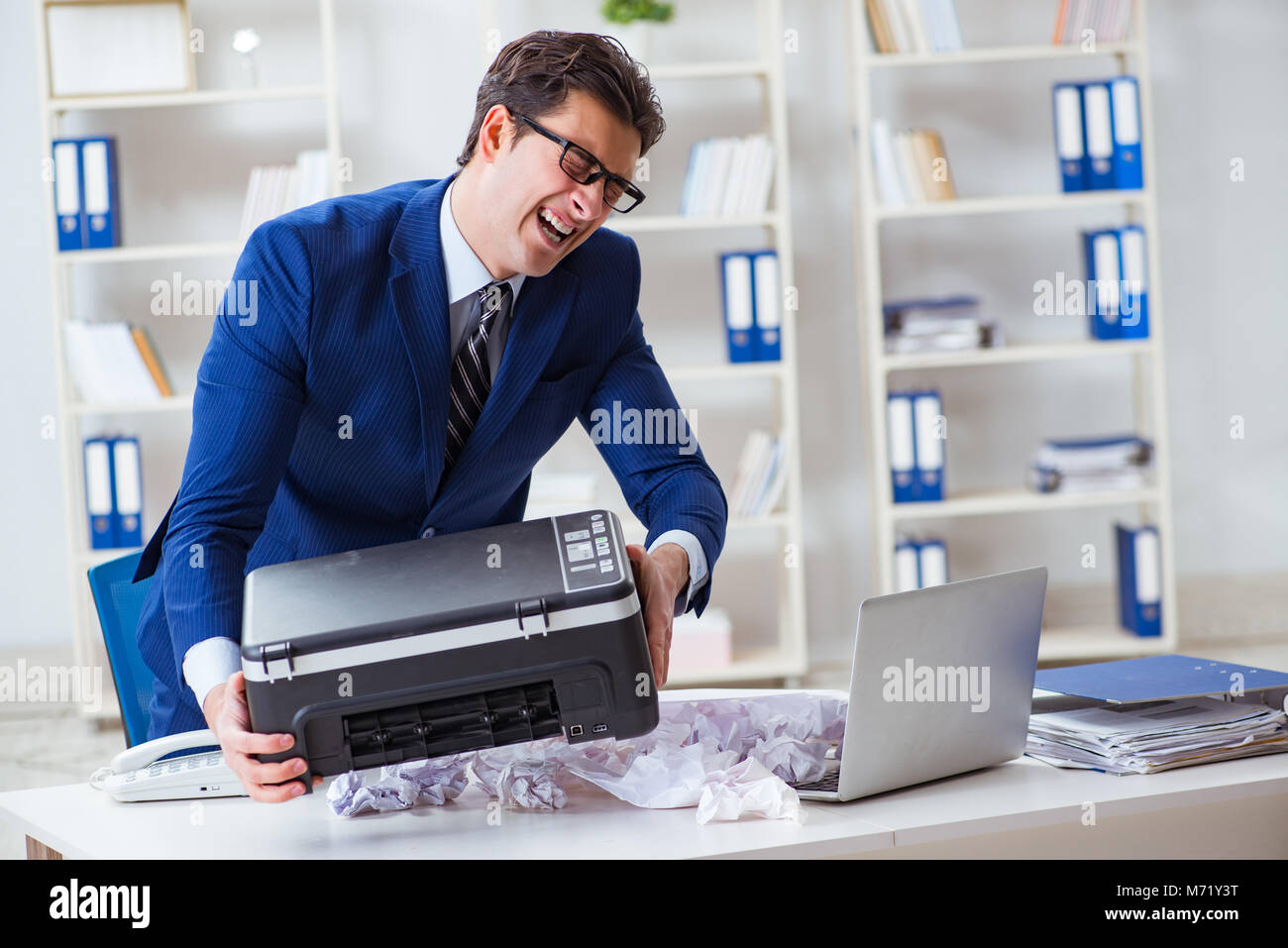Businessman angry at copying machine jamming papers Stock Photo - Alamy