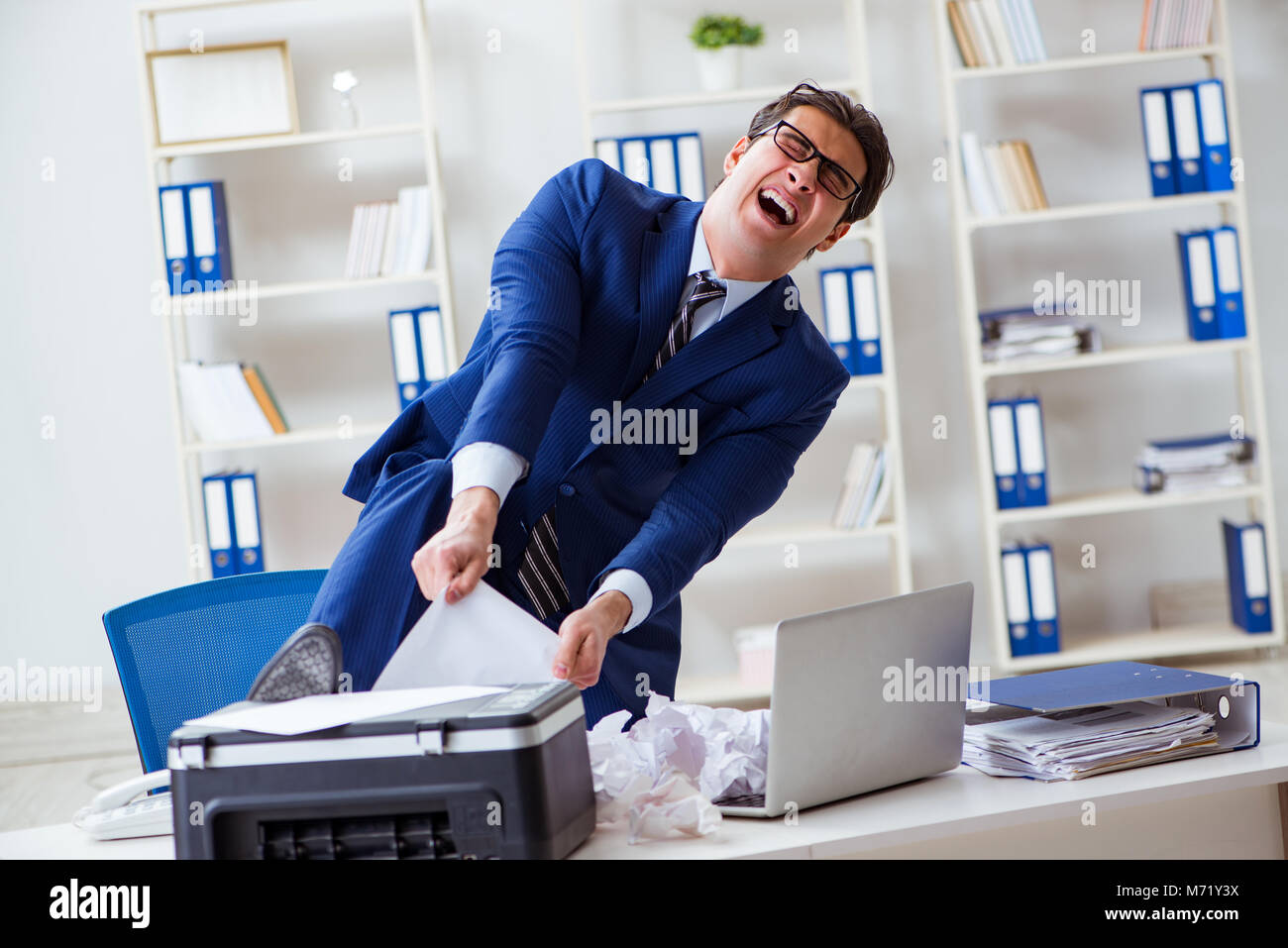 Businessman angry at copying machine jamming papers Stock Photo - Alamy