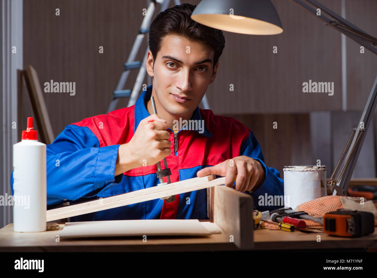 Young man gluing wood pieces together in DIY concept Stock Photo - Alamy