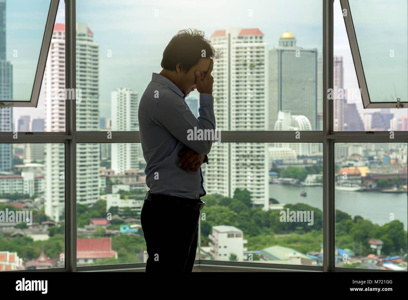 depressed man standing face in hands on the interior Skyscraper with ...