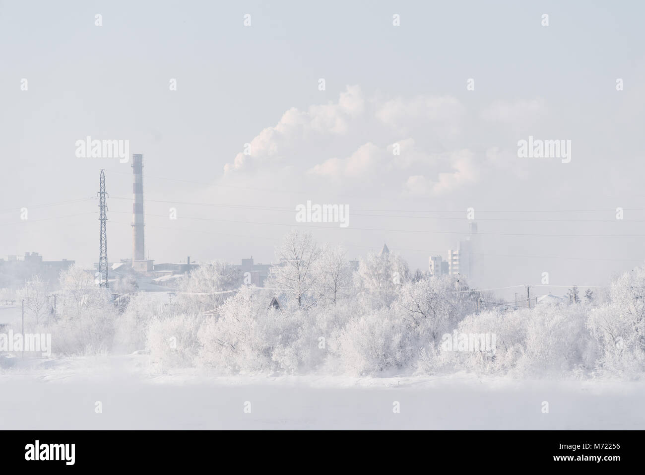 Snow covered on trees with industrial factory and smoke on the sky ...