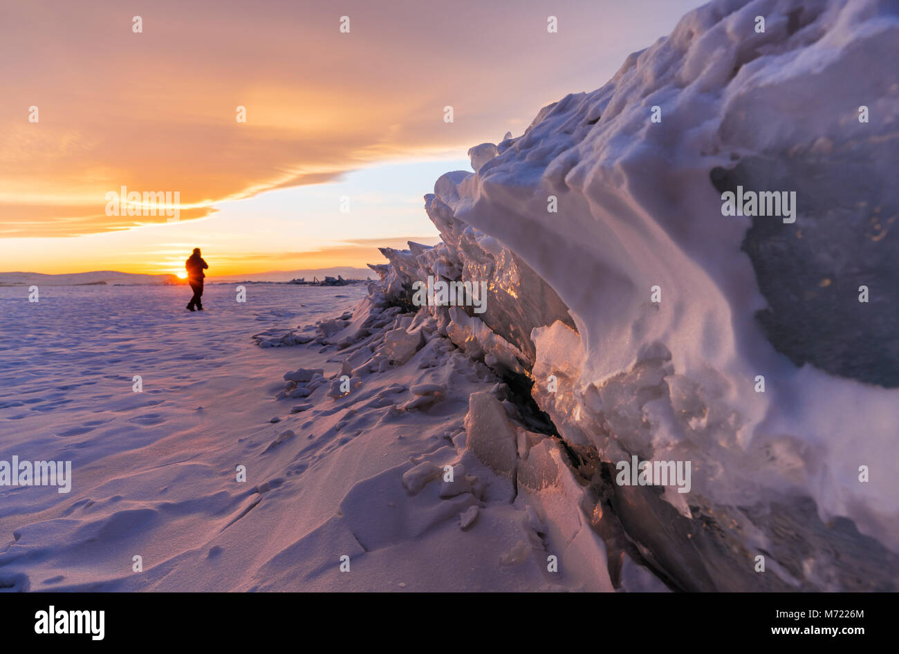 Winter landscape in sunset, Cracked frozen ice of lake covered by snow ...