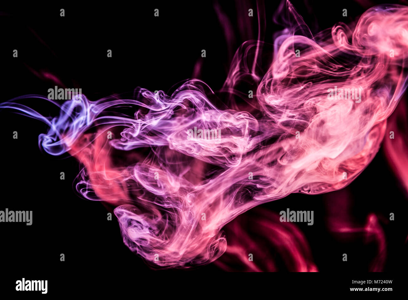 Dense multicolored smoke of pink colors on a black isolated background ...