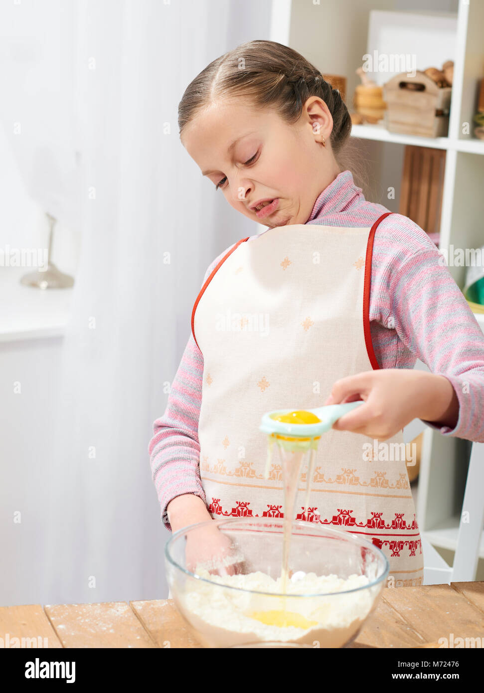Girl cooking and having fun at home, breaking egg and making faces ...