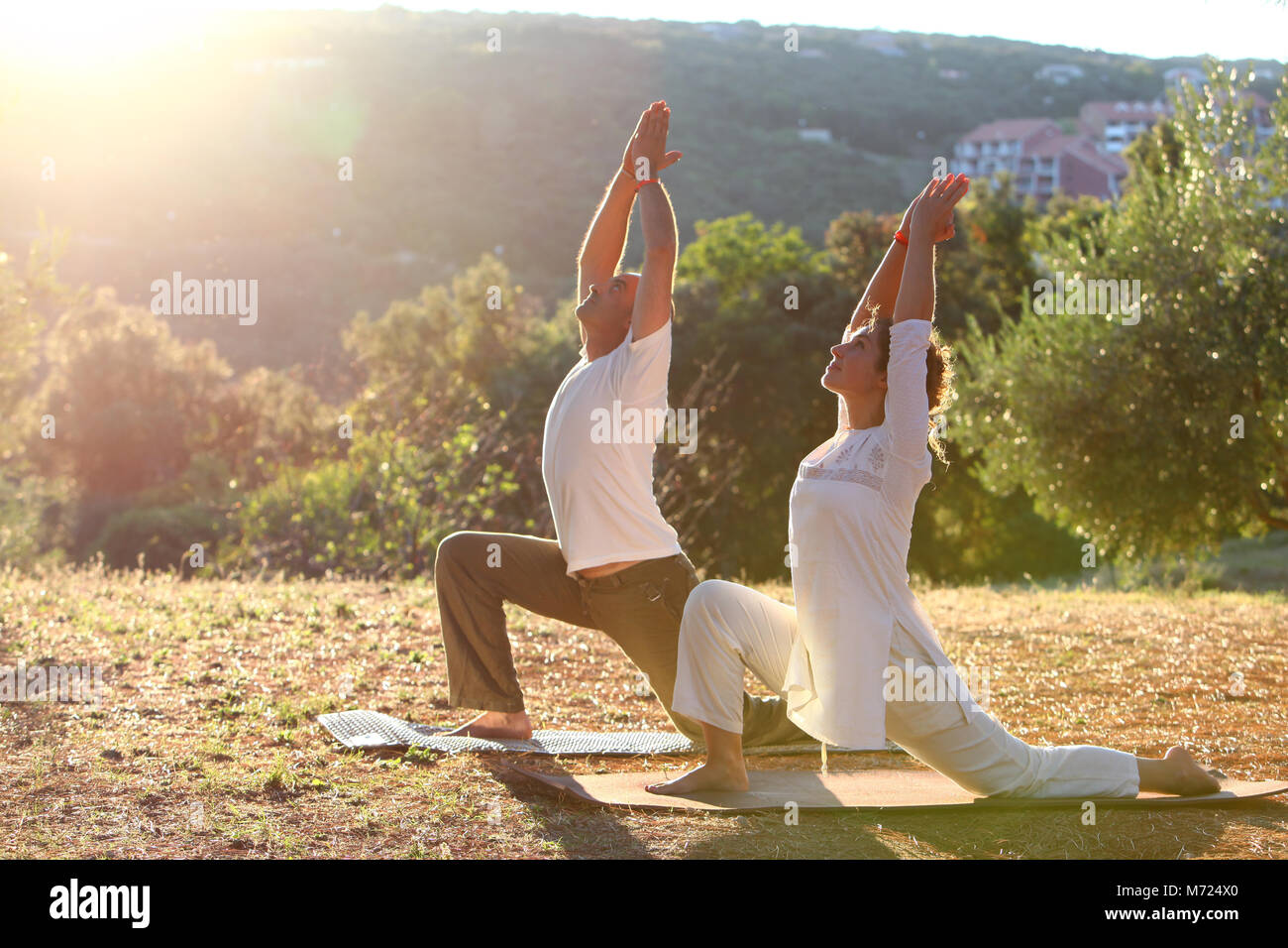 Young couple practice yoga outside in nature during sunrise on their ...