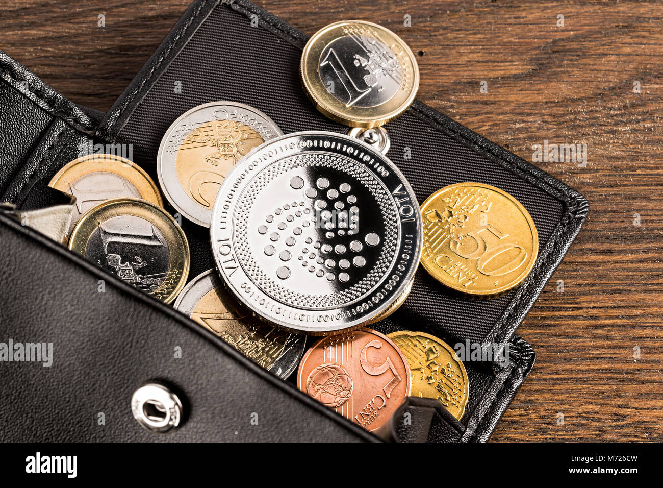 silver iota crypto currency coin on euro coins in leather wallet on ...