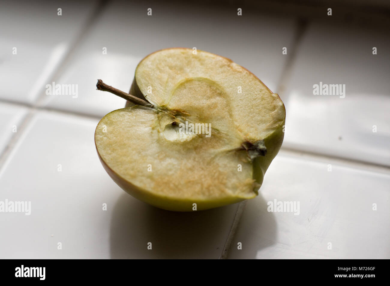 AN APPLE SLICED IN HALF ON A WHITE TILED SURFACE Stock Photo - Alamy