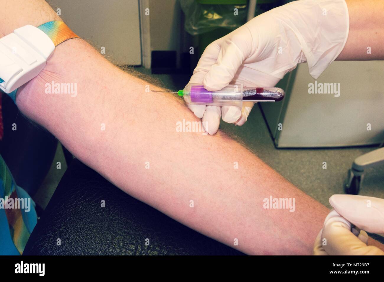 Blood test being performed on a middle aged man's arm / / blood being ...